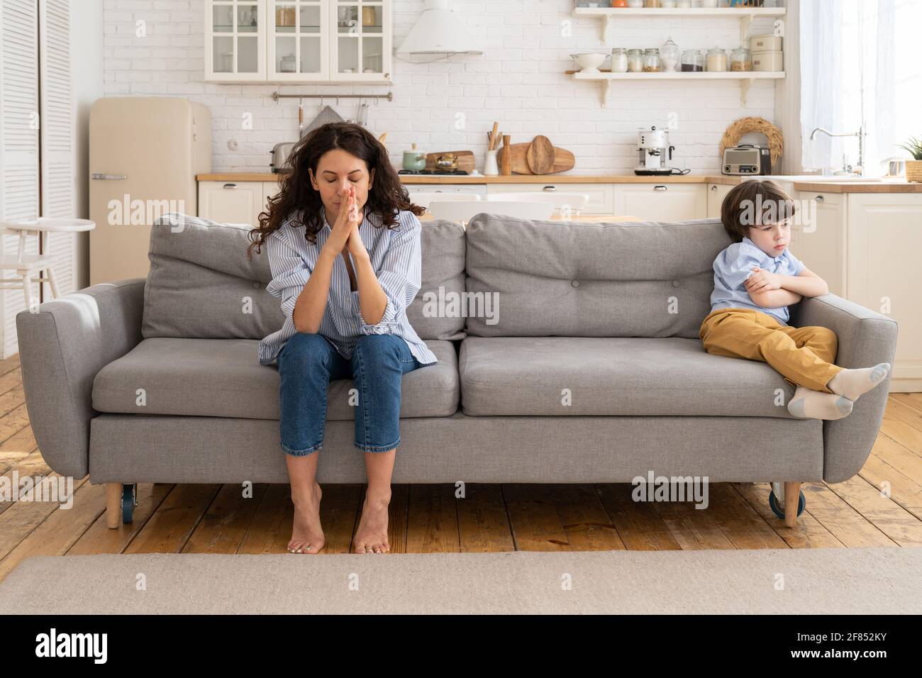 Offended mom and son sit on couch in living room avoid talking looking ...