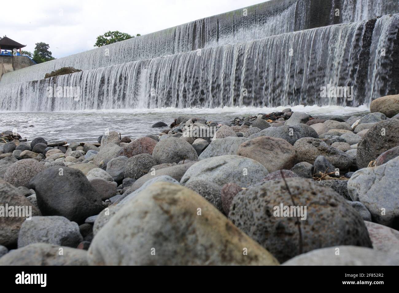 a two-story waterfall with little pebbles on the shore Stock Photo - Alamy