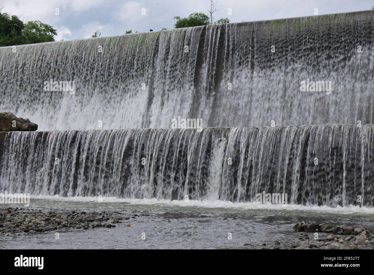 a beautiful two-story waterfall with little pebbles on the shore Stock ...