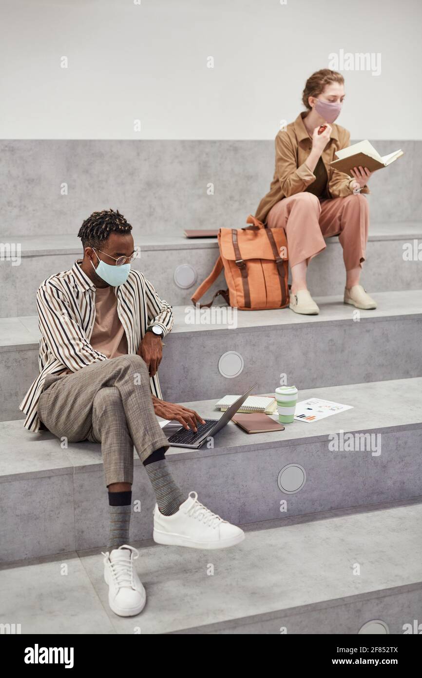 Vertical full length portrait of two young students working and ...