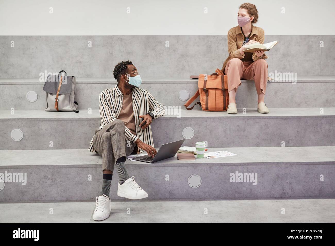 Wide angle portrait of two young students working and relaxing while ...