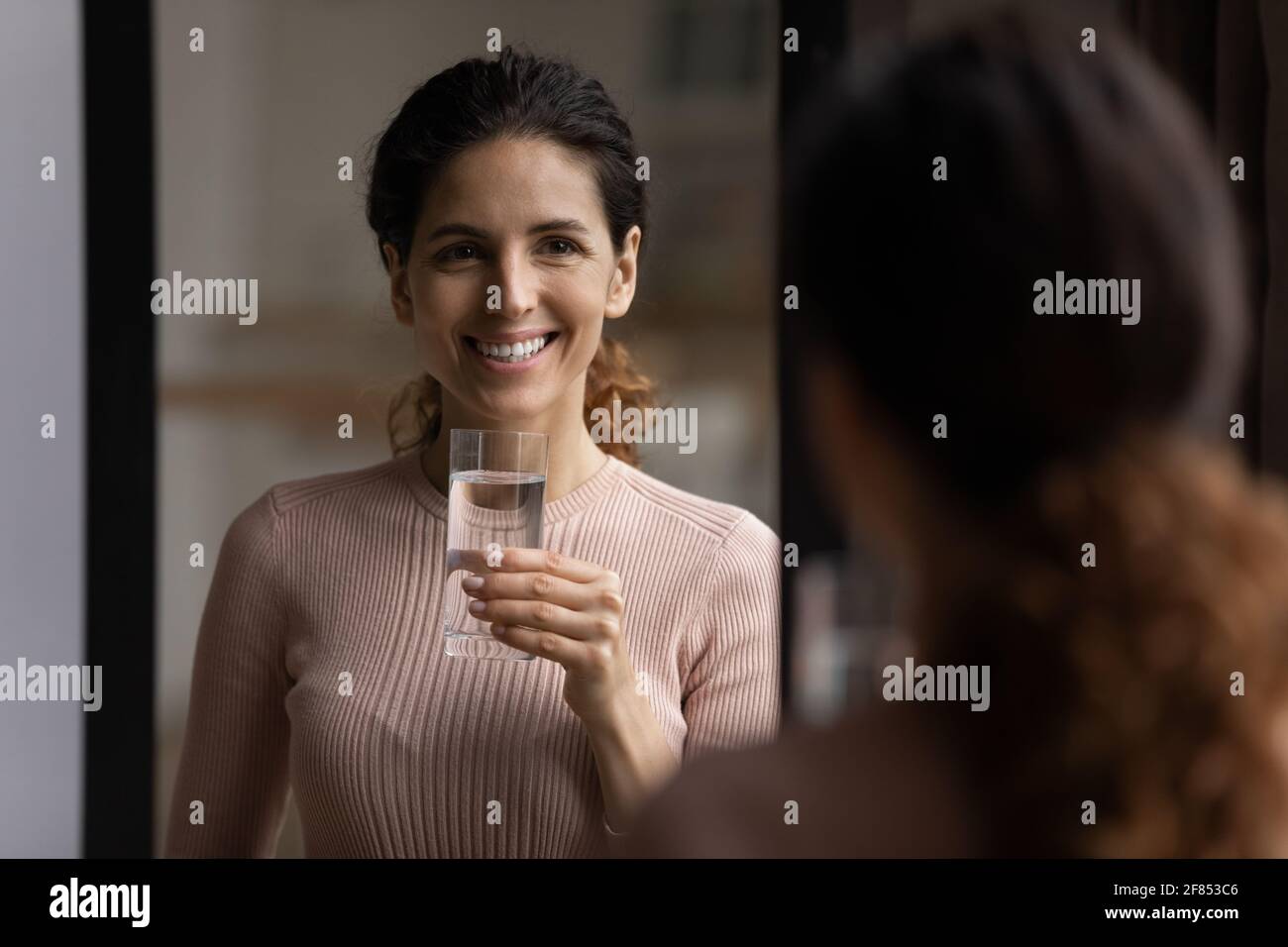 Beautiful latina lady stand by mirror hold glass of water Stock Photo ...