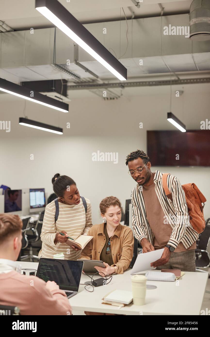 Vertical portrait of diverse group of students working together in ...