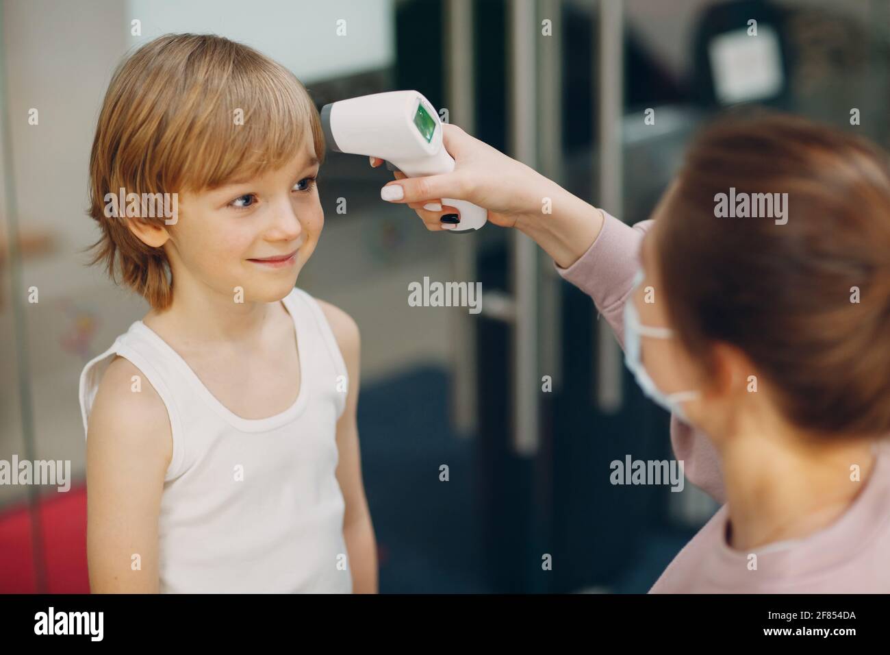 Child temperature measurement by laser thermometer at kindergarten ...