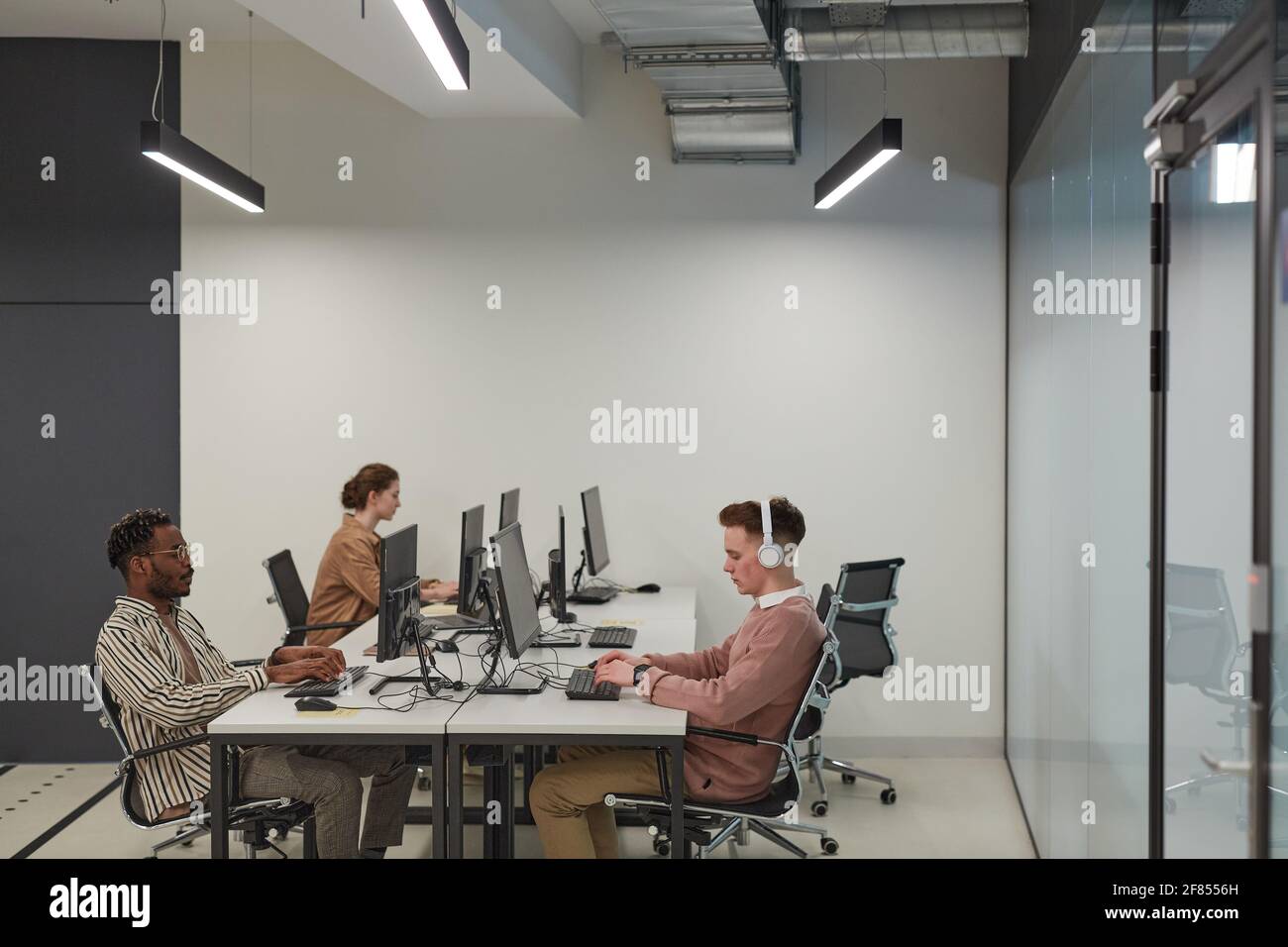 Wide angle view at group of students using computers in school library ...