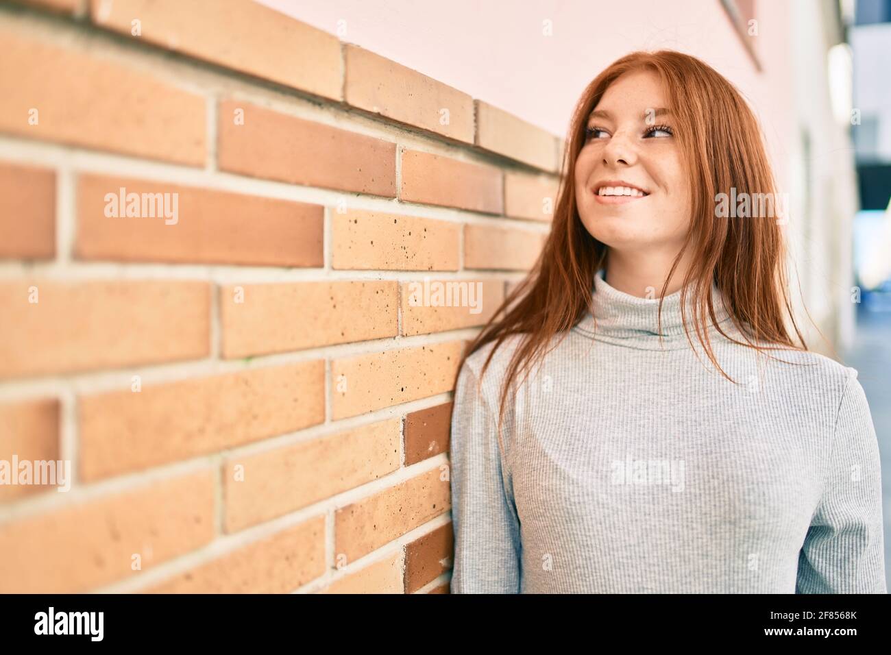 Young irish teenager girl smiling happy leaning on the wall at the city ...