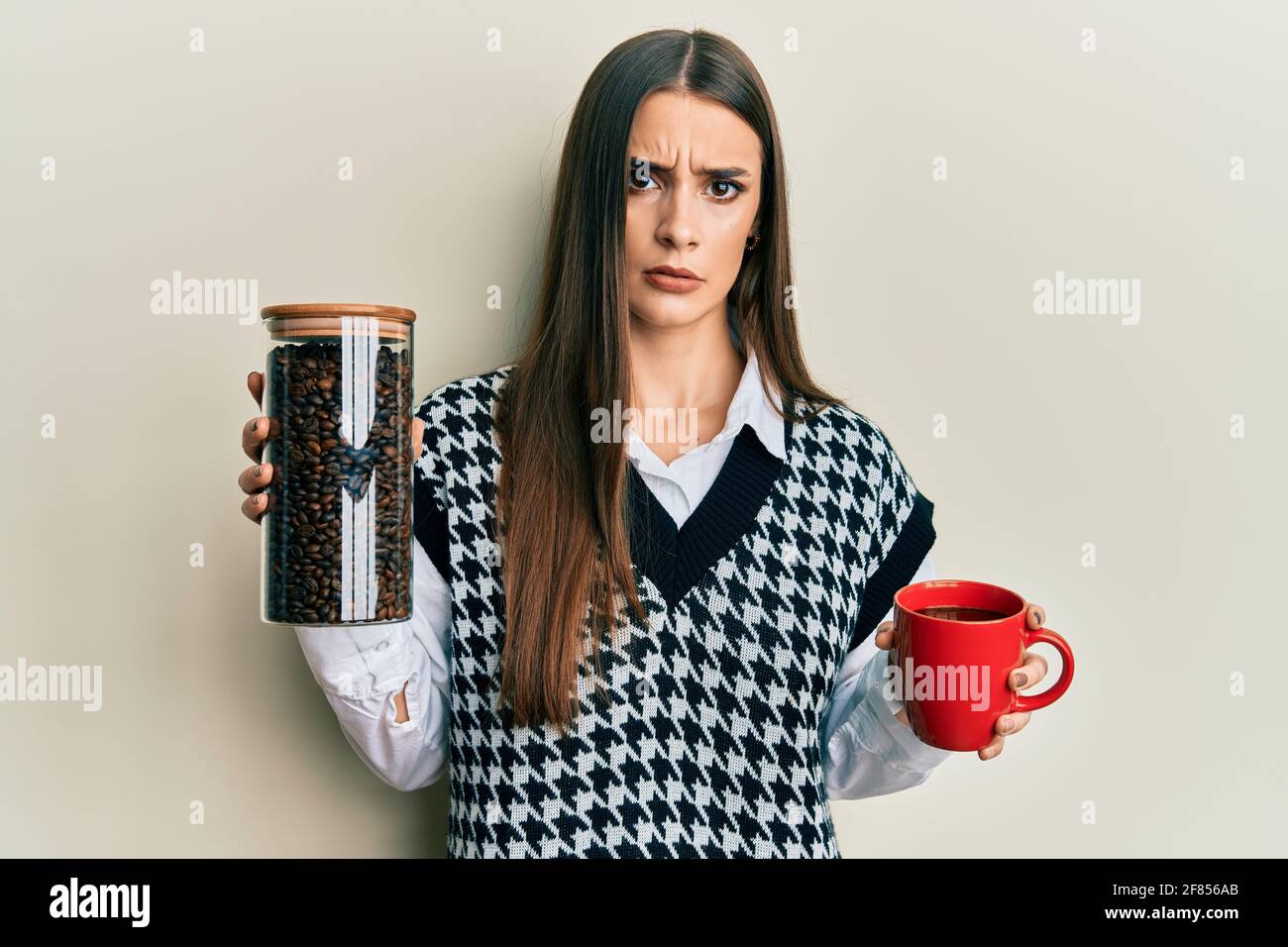 Beautiful brunette young woman holding jar with coffee beans and ...