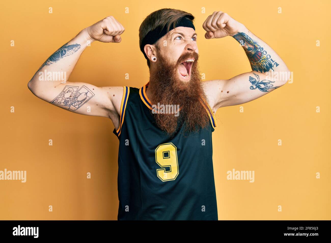Redhead man with long beard wearing basketball uniform showing muscles ...