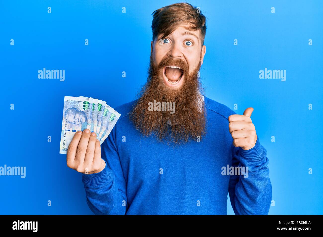 Young irish redhead man holding south african 100 rand banknotes ...