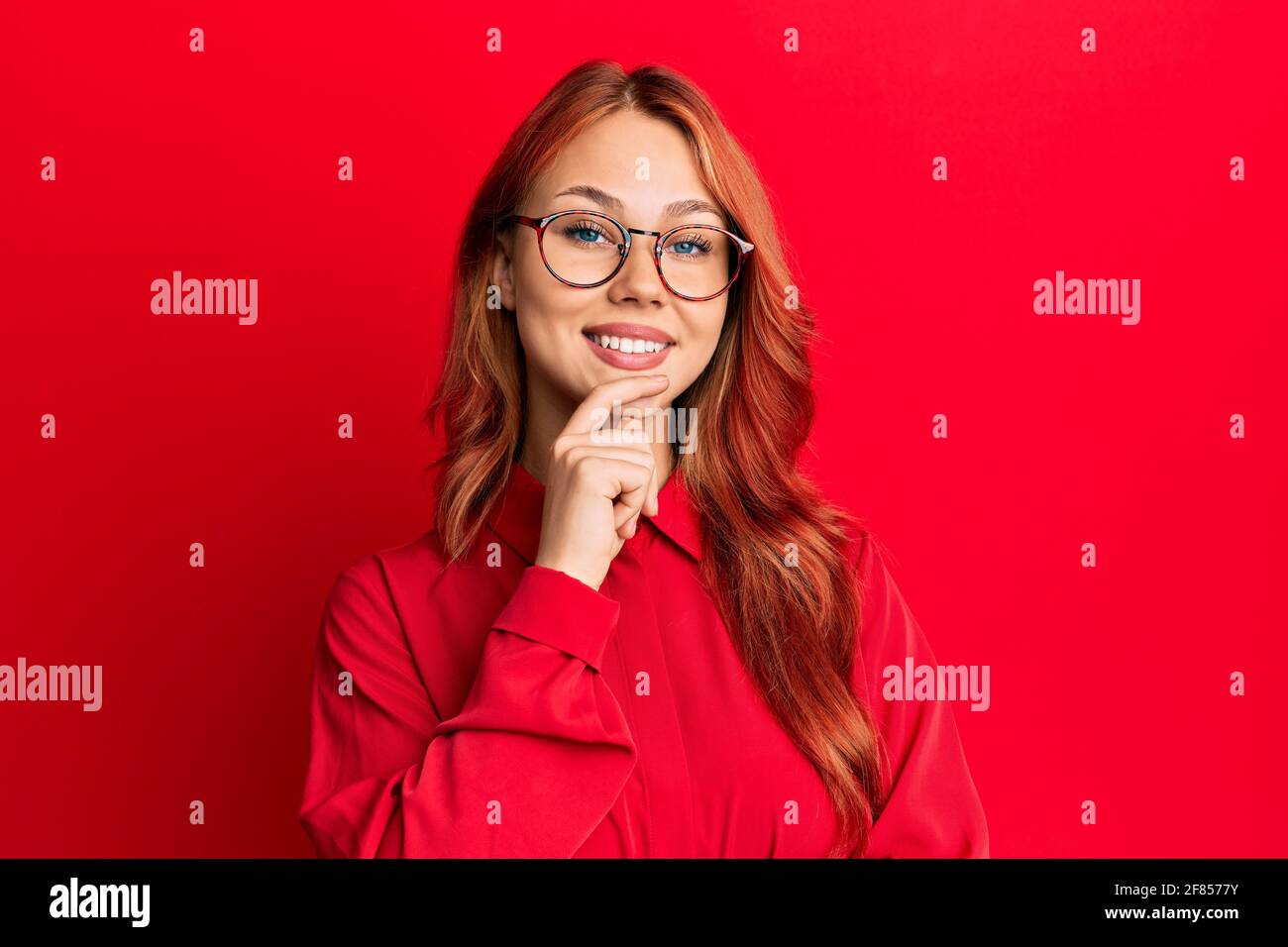 Young beautiful redhead woman wearing casual clothes and glasses over ...