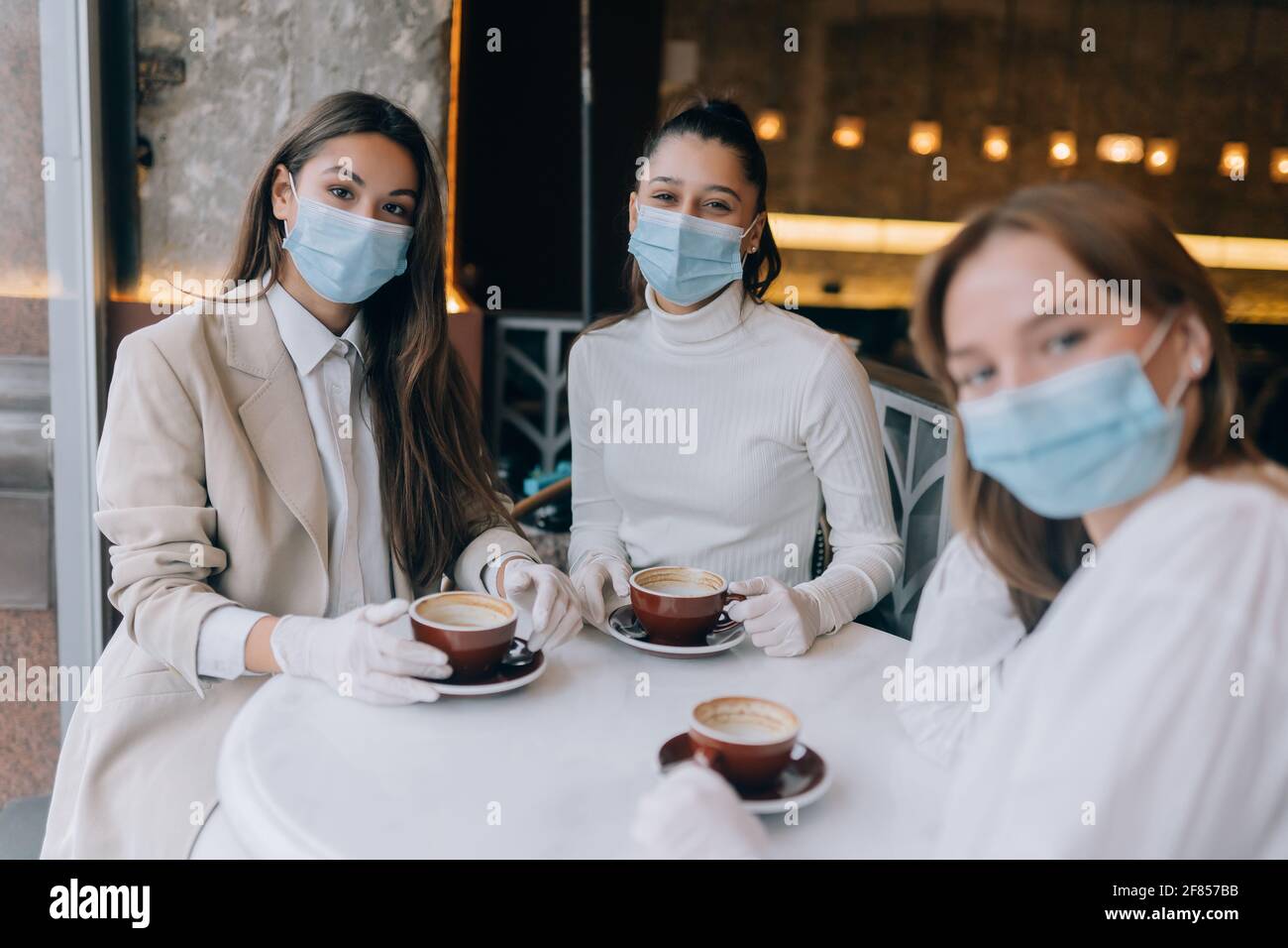 Friends girls met in a cafe. Wear medical protective masks Stock Photo ...