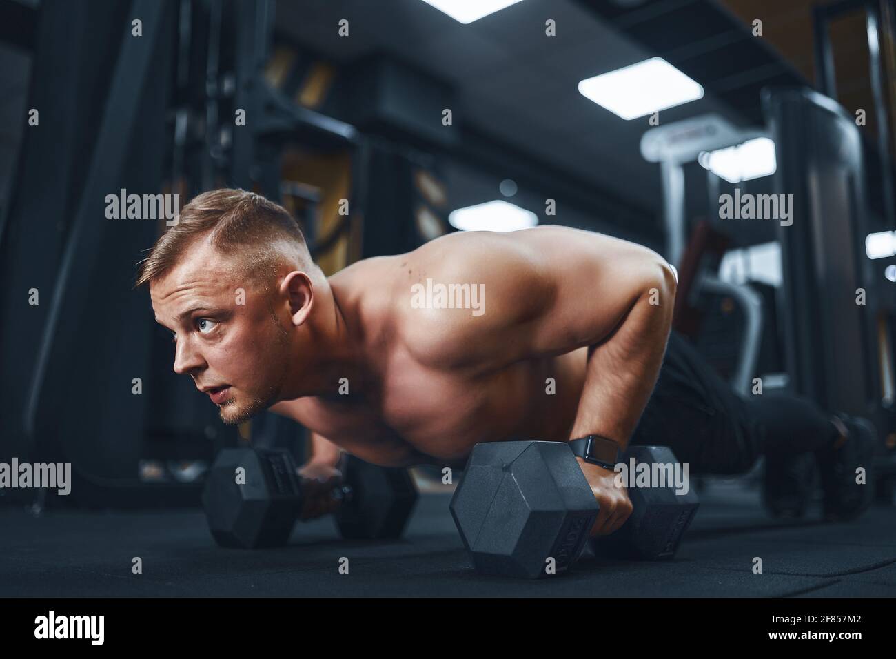 Young athletic man doing push-ups in gym. Muscular and strong guy ...