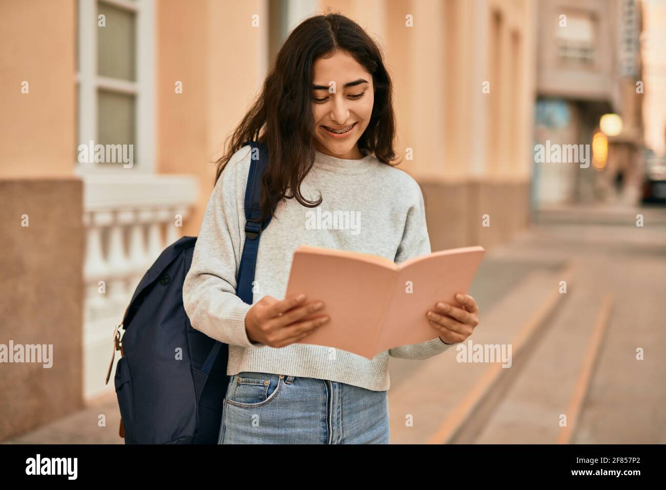 Young middle east student girl smiling happy reading book at the city ...