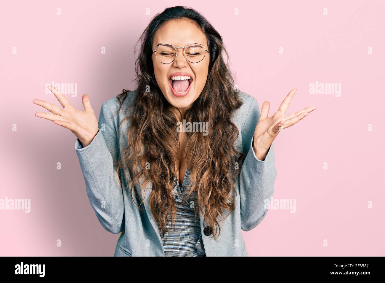 Young hispanic girl wearing business clothes and glasses celebrating ...