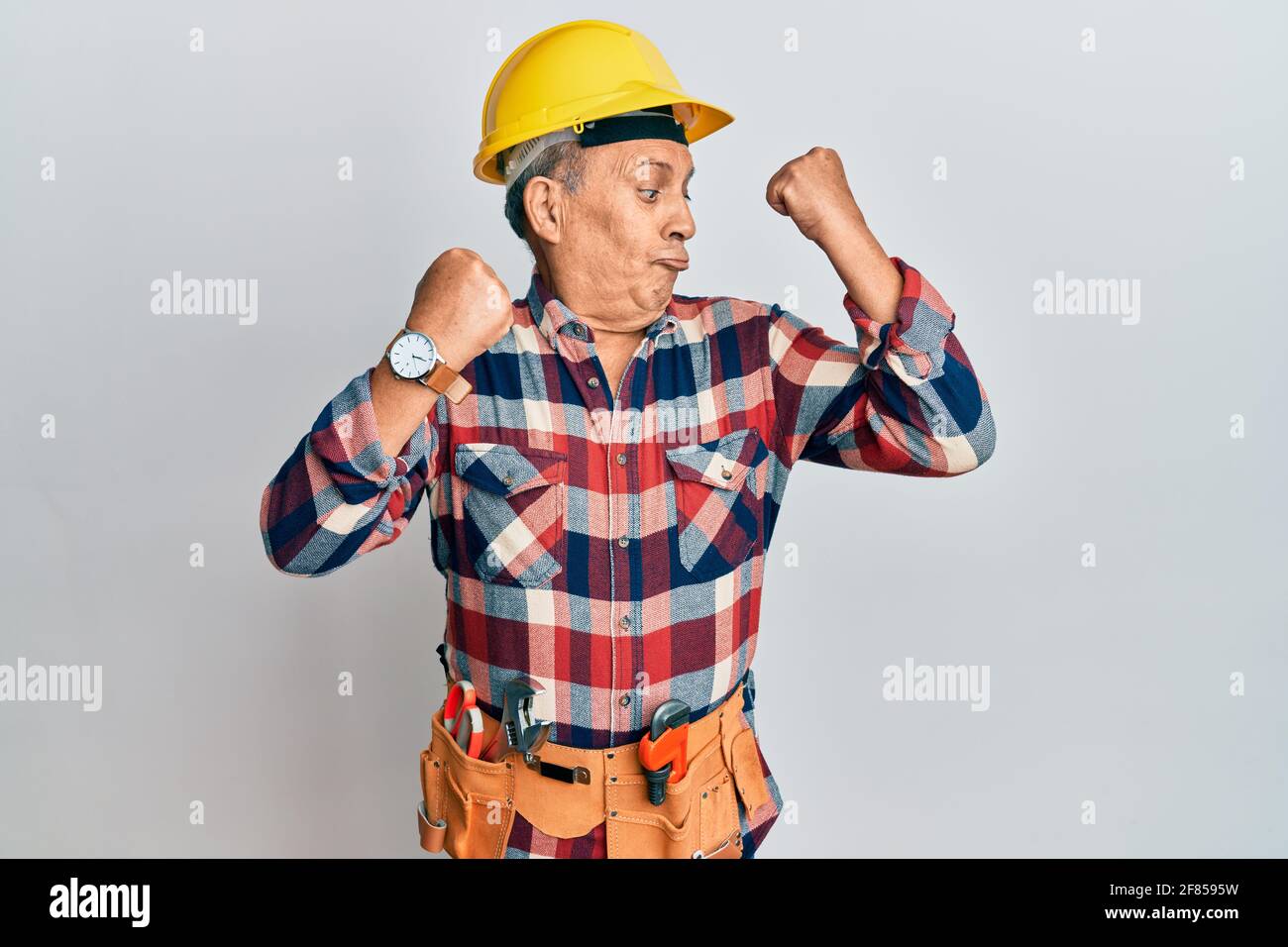 Senior hispanic man wearing handyman uniform showing arms muscles ...