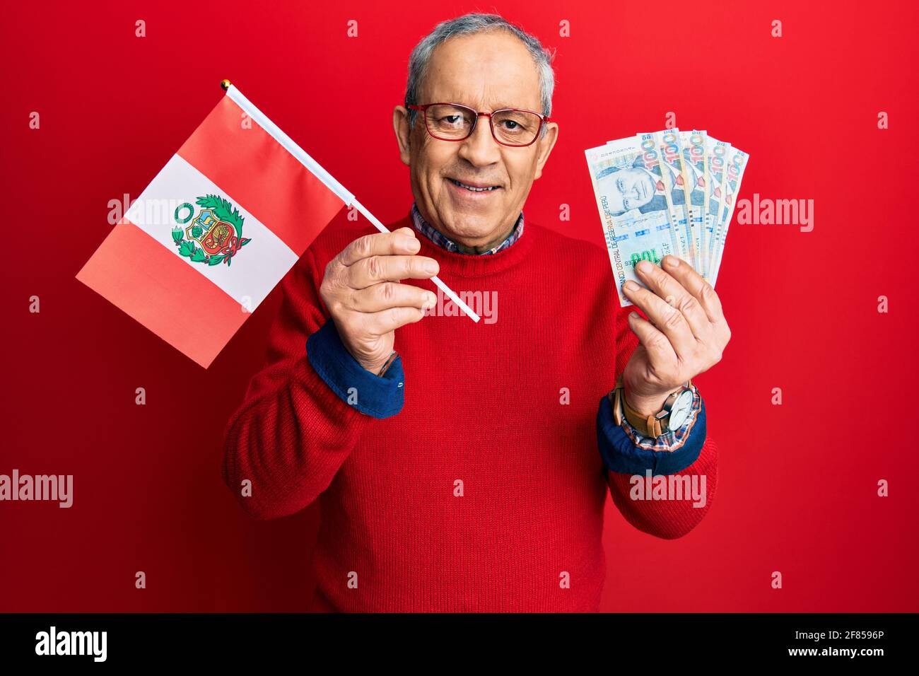 Handsome senior man with grey hair holding peru flag and peruvian sol ...