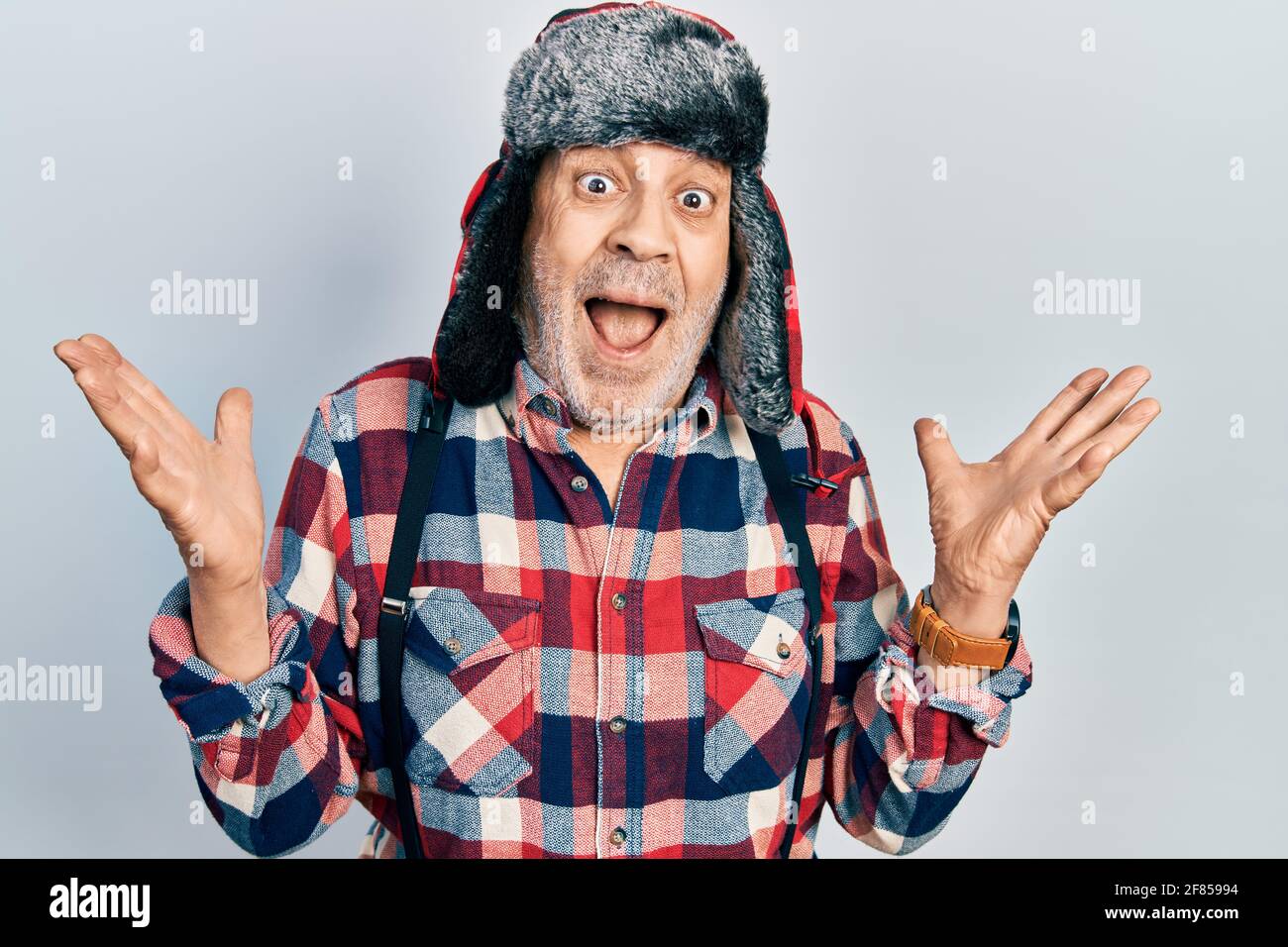 Handsome mature man wearing winter hat with ear flaps celebrating ...