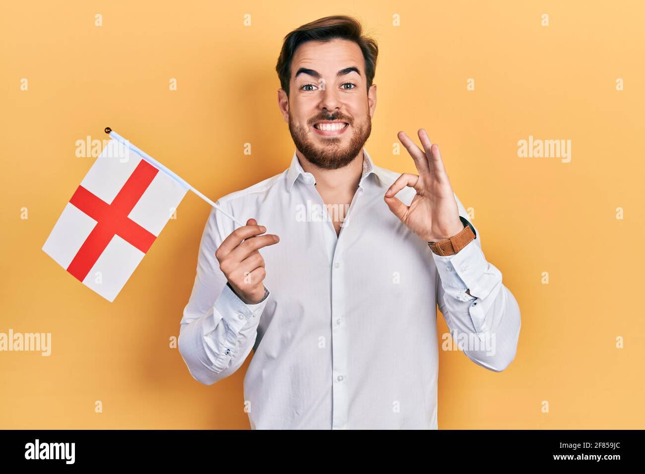 Handsome caucasian man with beard holding england flag doing ok sign ...