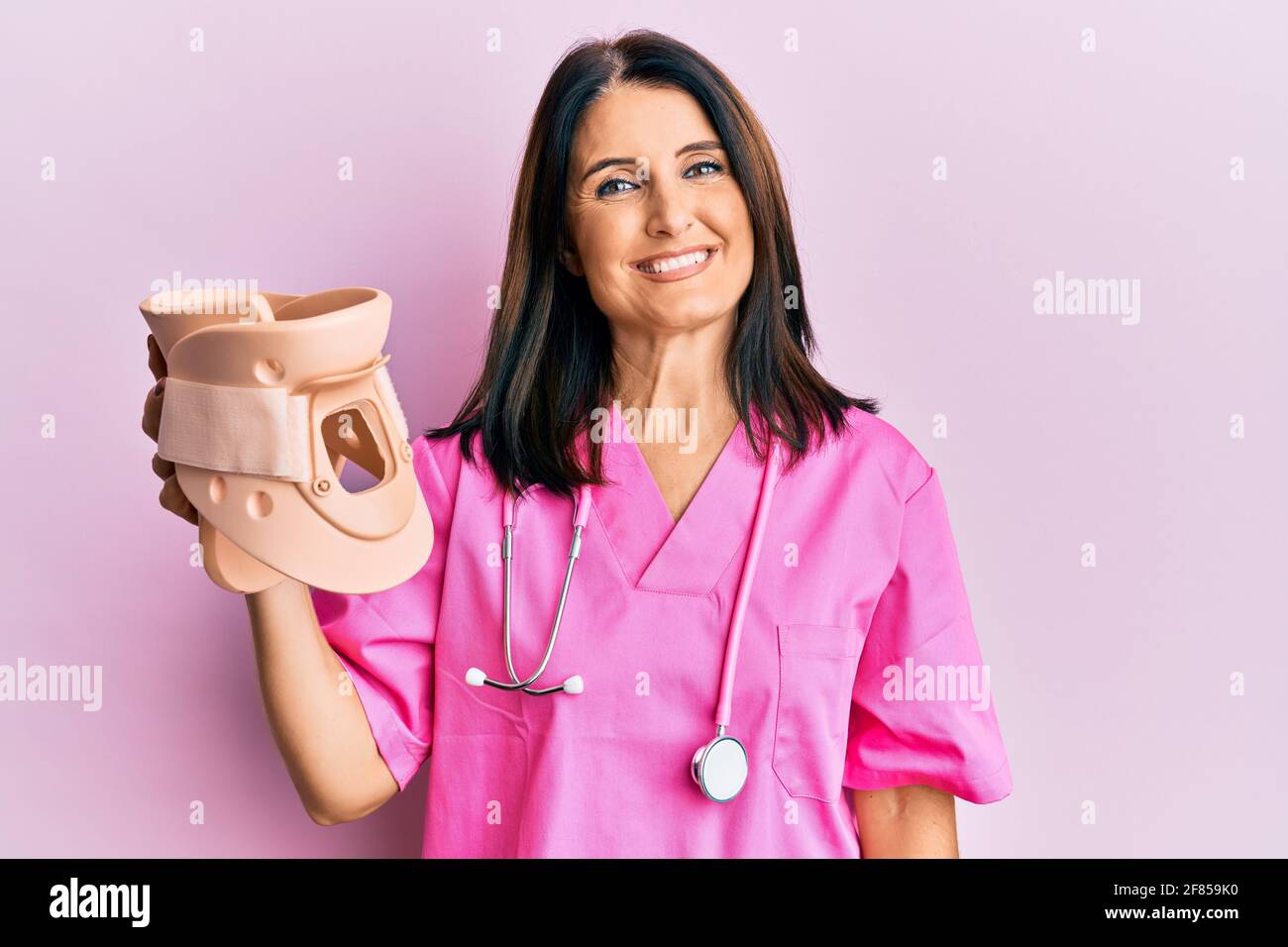 Middle age brunette doctor woman holding cervical neck collar looking ...