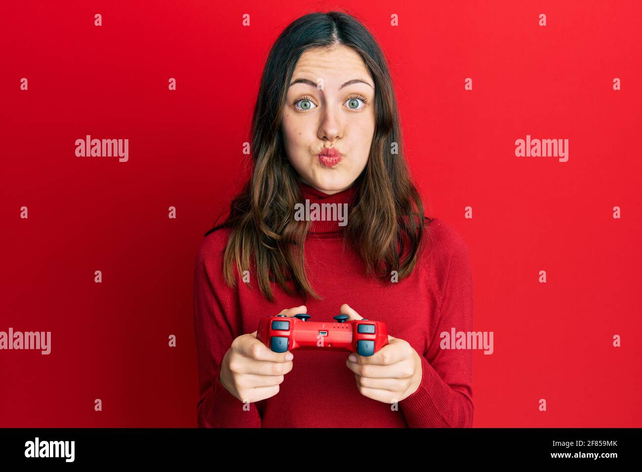 Young brunette woman playing video game holding controller puffing ...