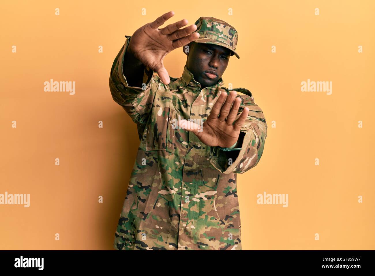 Young african american man wearing army uniform doing frame using hands ...