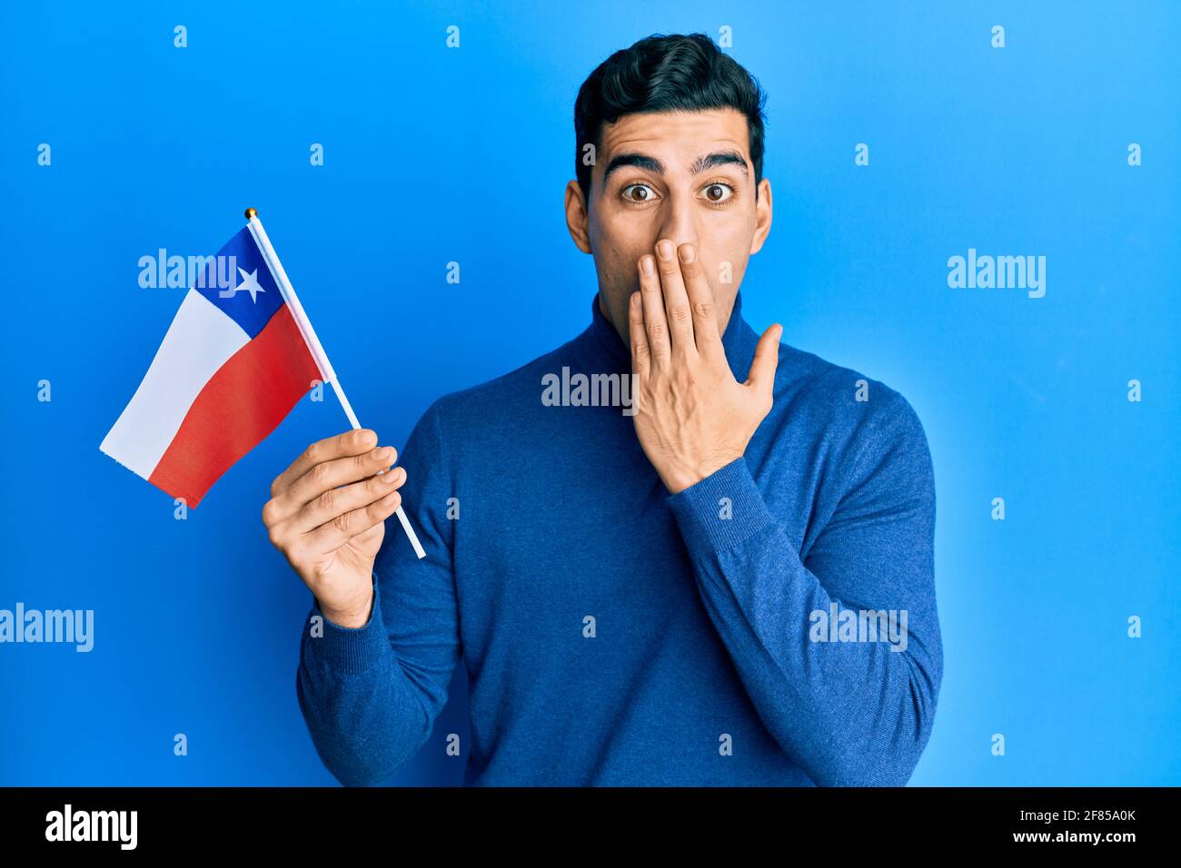 Handsome hispanic business man holding chile flag covering mouth with ...
