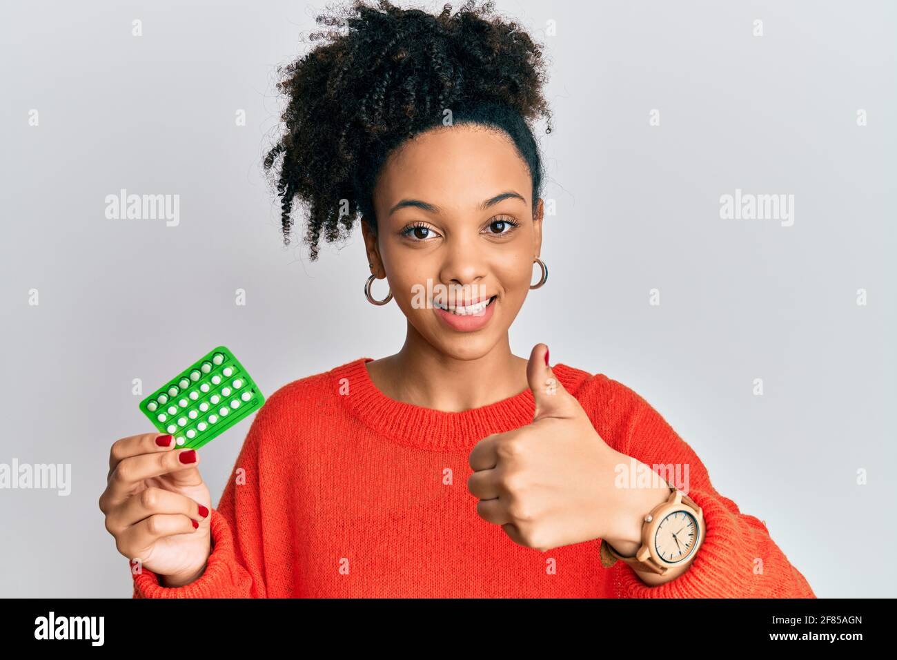 Young african american girl holding birth control pills smiling happy ...