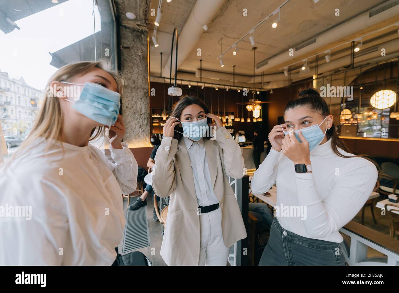 Caucasian women taking off a medical mask in a cafe Stock Photo - Alamy