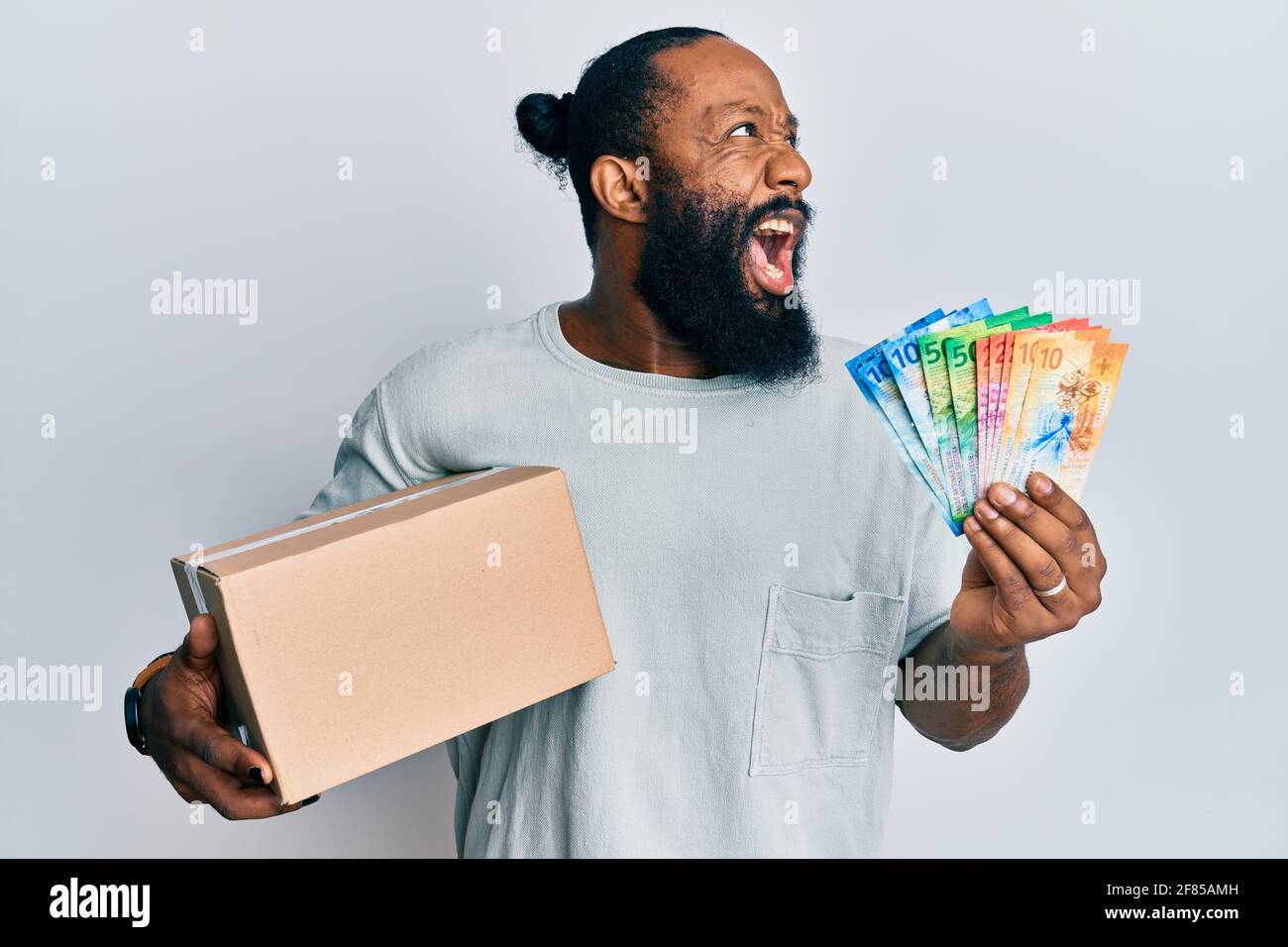 Young african american man holding delivery box and swiss franc ...