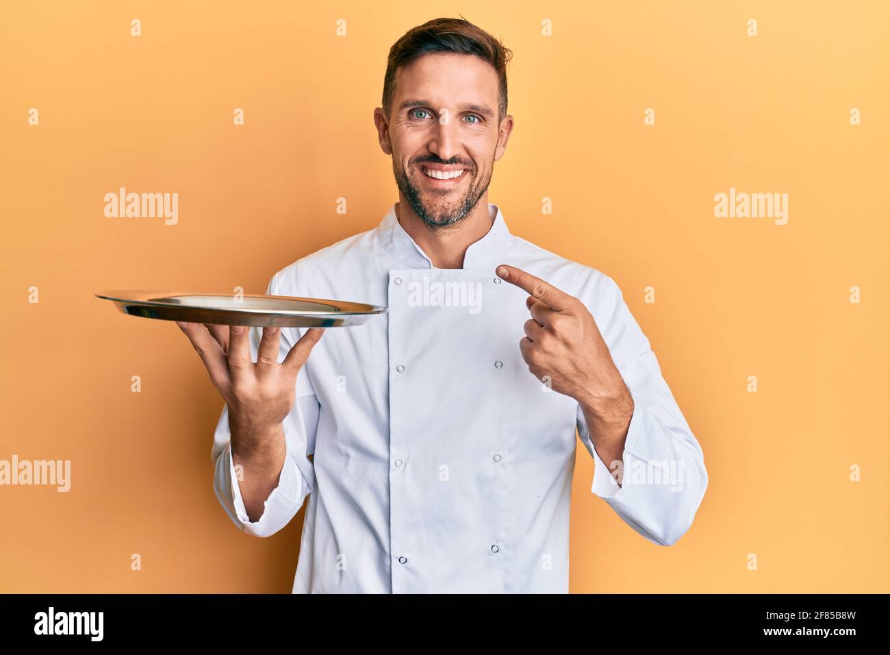 Handsome man with beard wearing chef uniform holding silver tray ...