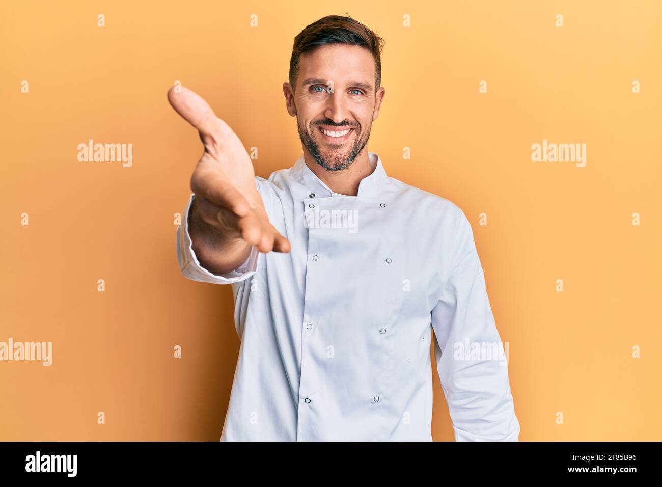 Handsome man with beard wearing professional cook uniform smiling ...