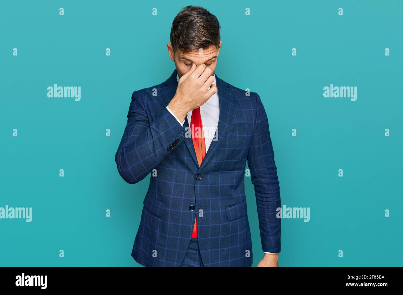 Handsome man with beard wearing business suit and tie tired rubbing ...