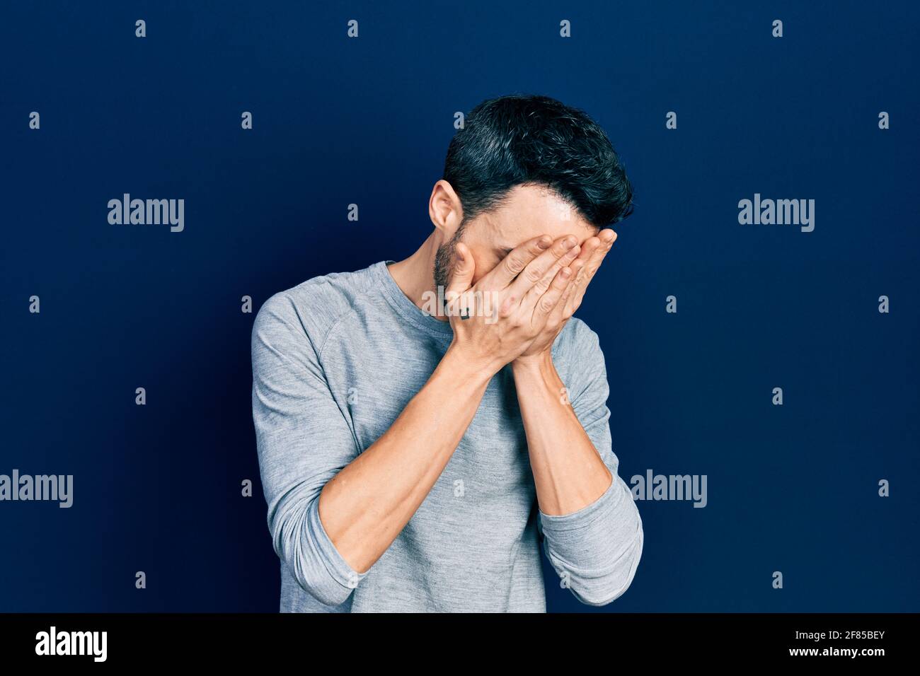 Young hispanic man wearing casual clothes with sad expression covering ...