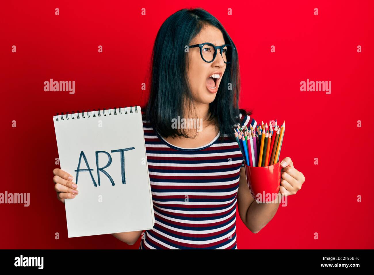 Beautiful asian young woman holding art notebook and colored pencils ...