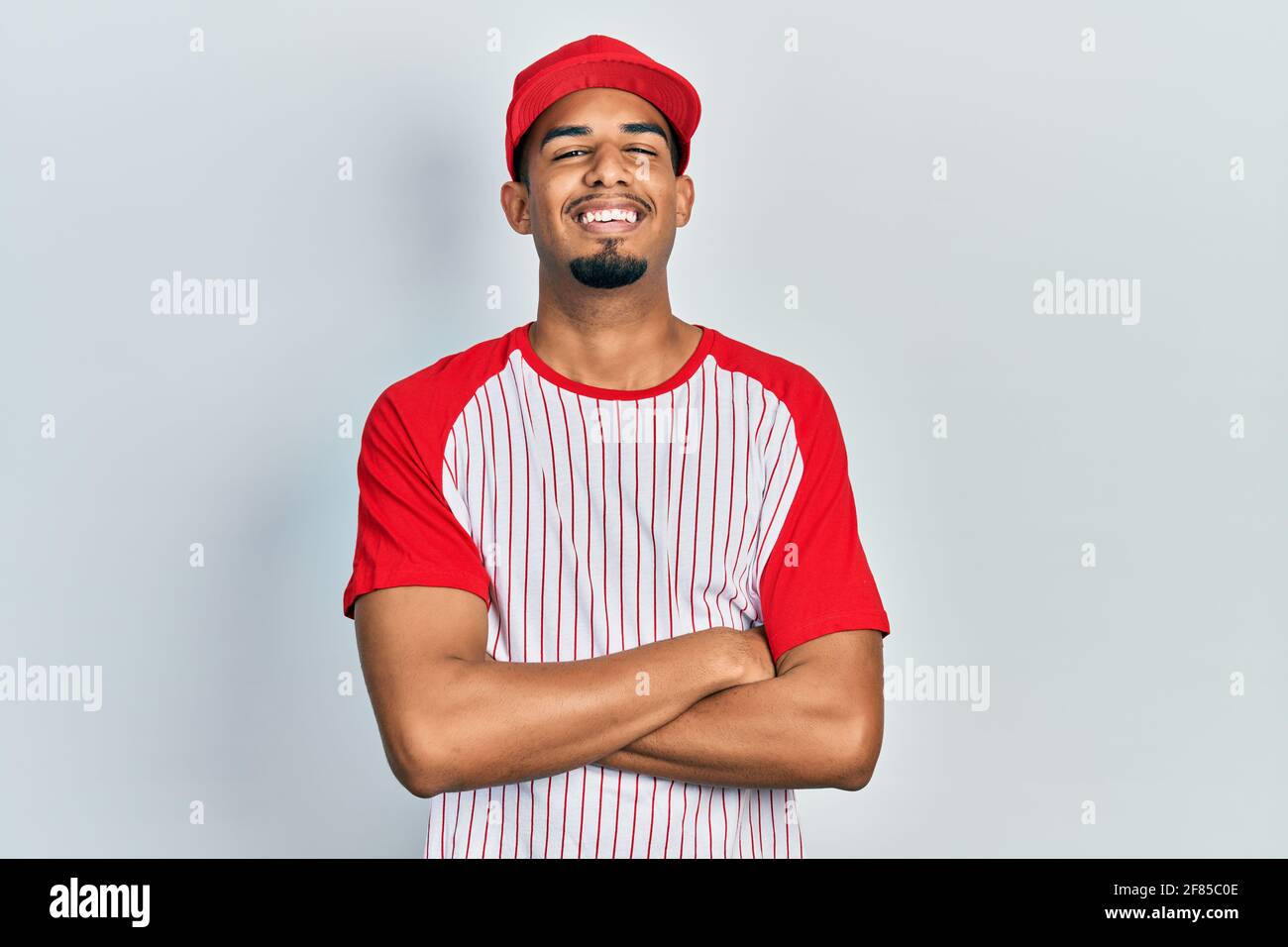 Young african american man wearing baseball uniform scared and amazed ...