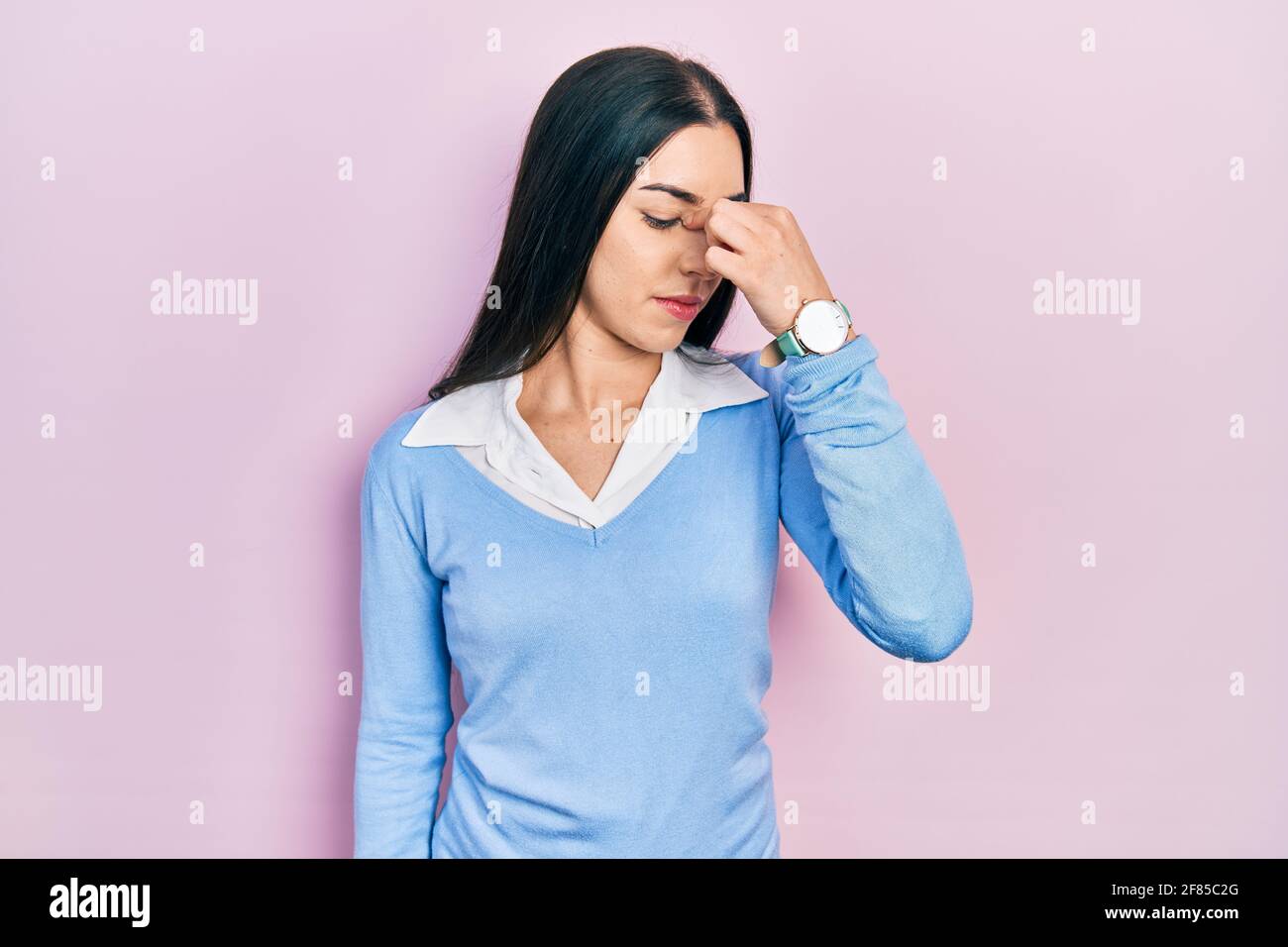 Beautiful woman with blue eyes standing over pink background tired ...