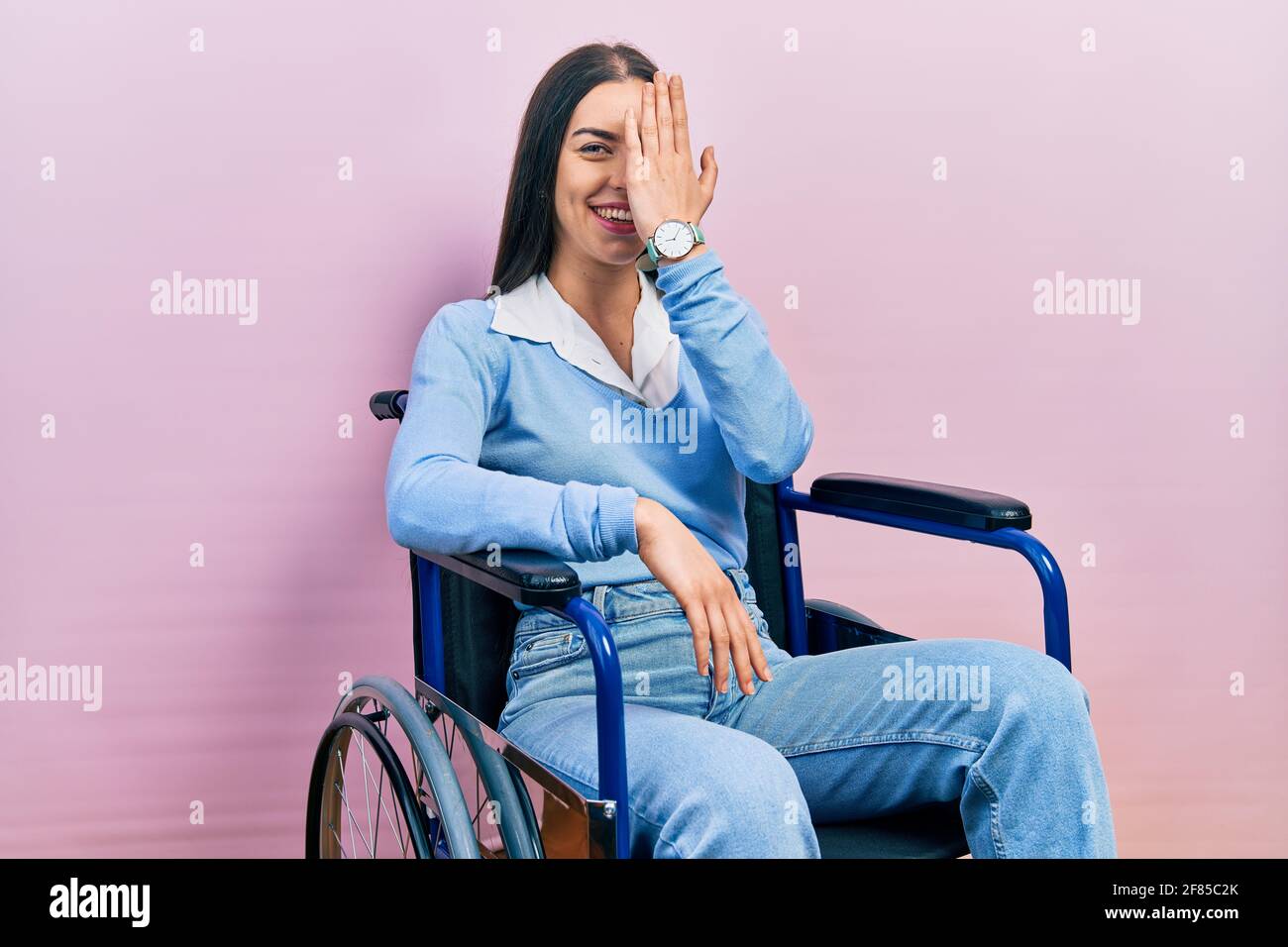 Beautiful woman with blue eyes sitting on wheelchair covering one eye ...
