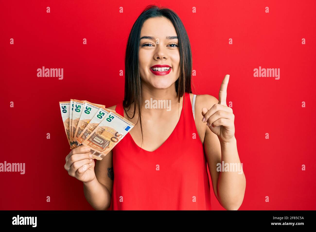 Young hispanic girl holding euro banknotes smiling with an idea or ...