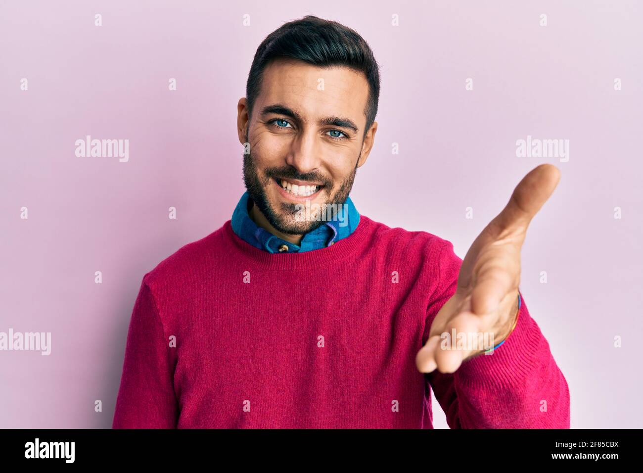 Young hispanic man wearing casual clothes smiling friendly offering ...