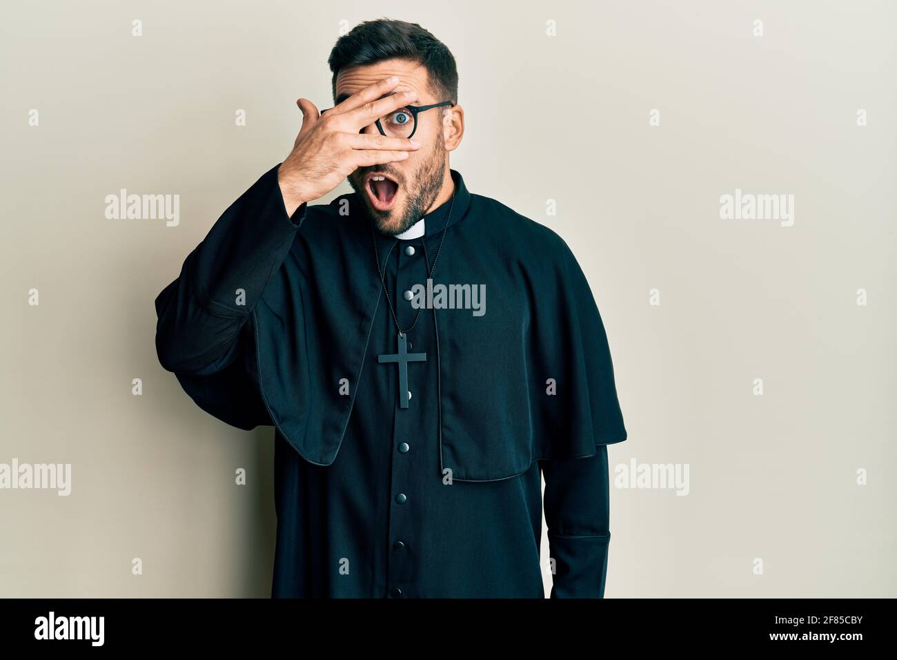 Young hispanic man wearing priest uniform standing over white ...