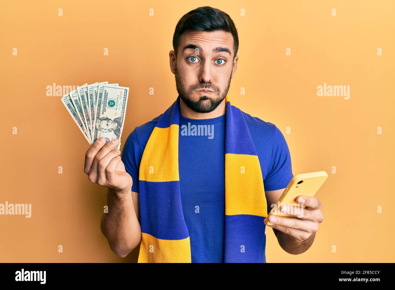 Young hispanic man football supporter using smartphone holding usa ...
