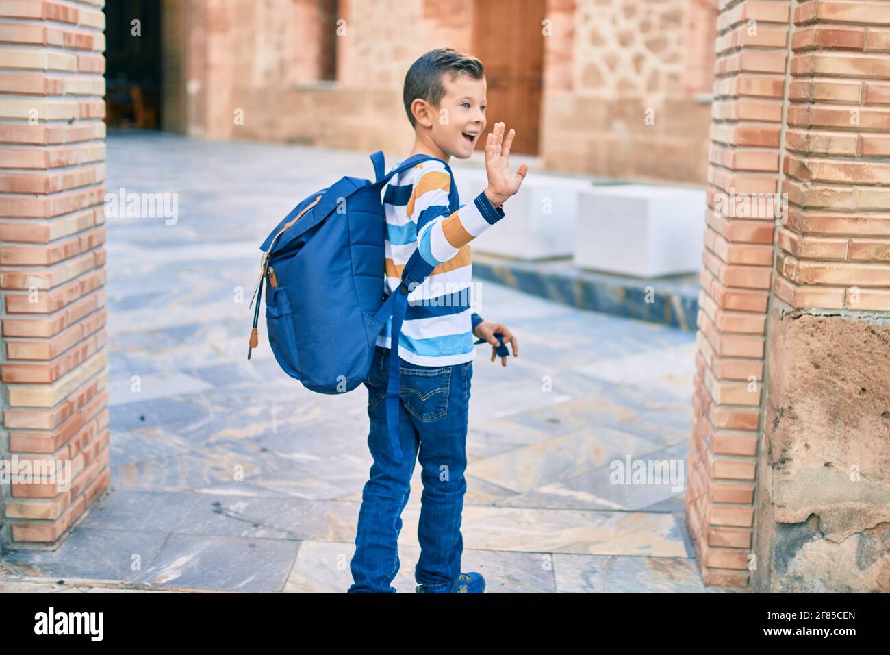 Adorable caucasian student boy smiling happy saying goodbye with hand ...