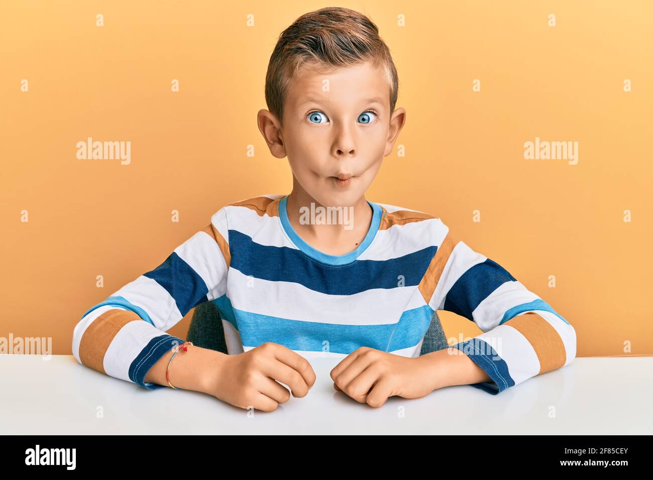 Adorable caucasian kid wearing casual clothes sitting on the table ...