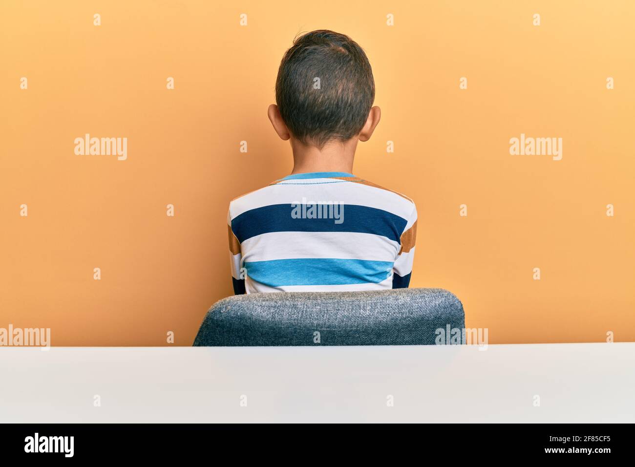 Adorable caucasian kid wearing casual clothes sitting on the table ...