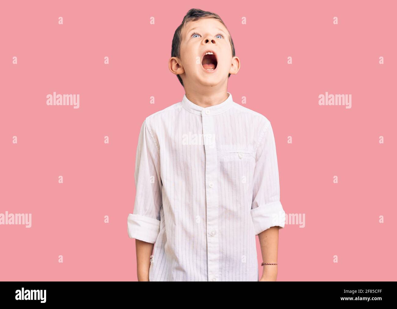 Cute blond kid wearing elegant shirt angry and mad screaming frustrated ...