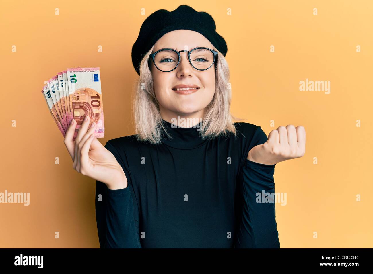 Young blonde girl holding euro banknotes screaming proud, celebrating ...
