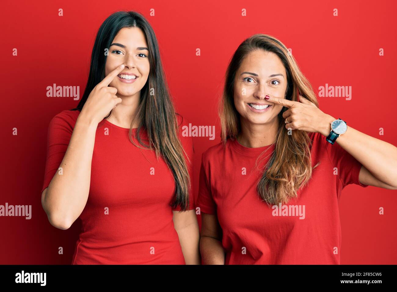 Hispanic family of mother and daughter wearing casual clothes over red ...