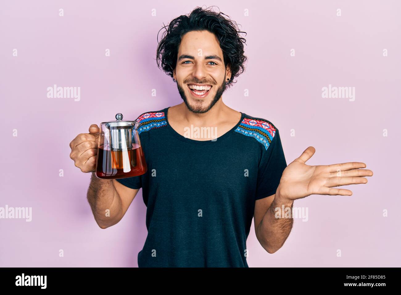 Handsome hispanic man holding traditional tea pot celebrating ...