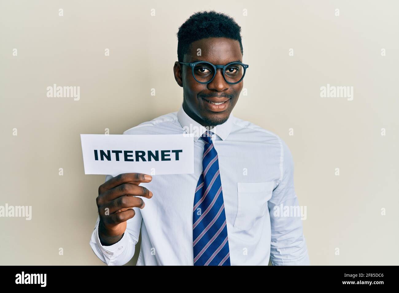 Handsome black man holding paper with internet word looking positive ...