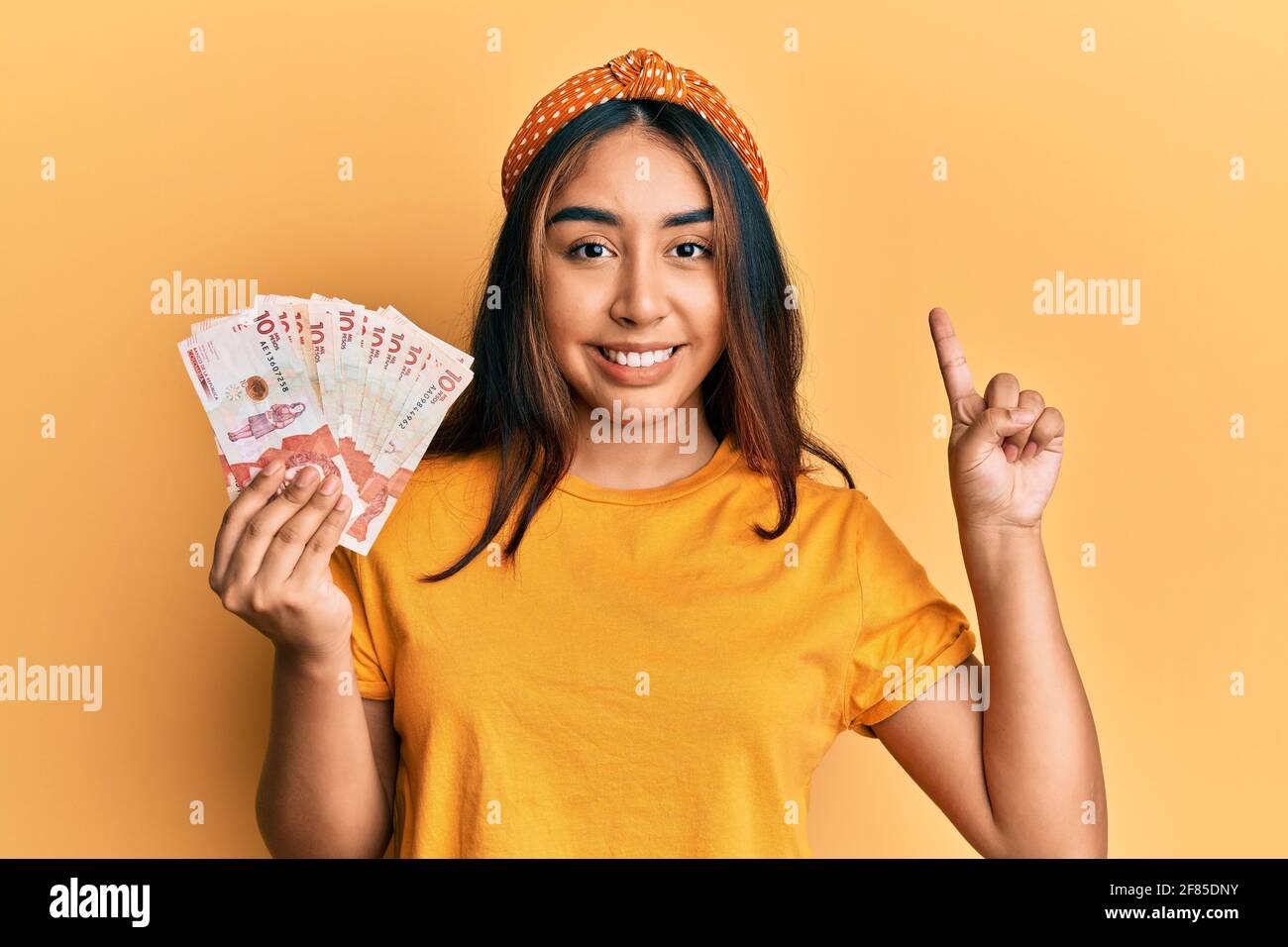 Young latin woman holding colombian pesos smiling with an idea or ...